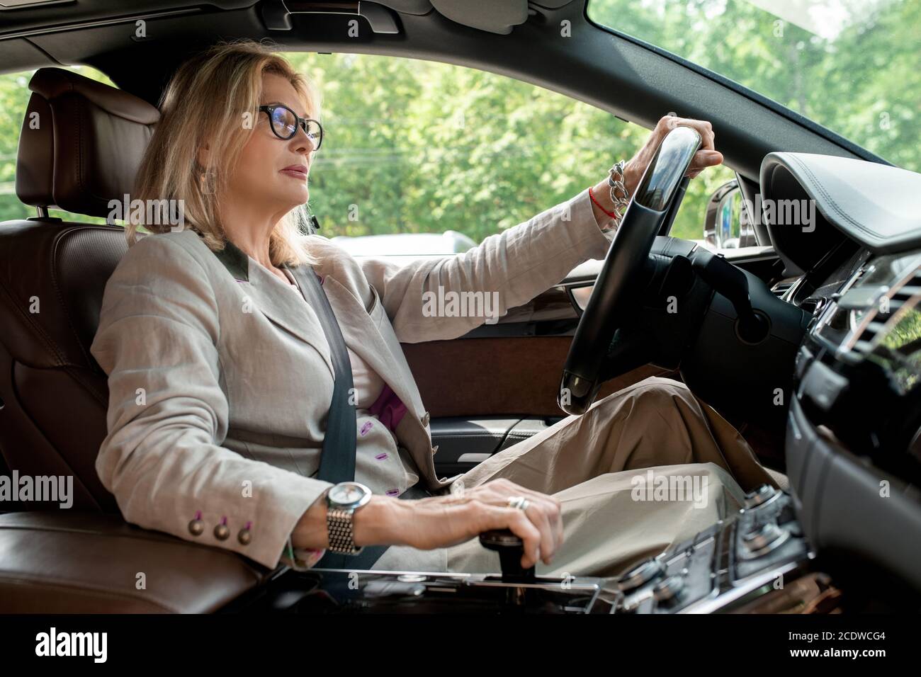 Businesswoman sitting by open window in car and driving to office for ...