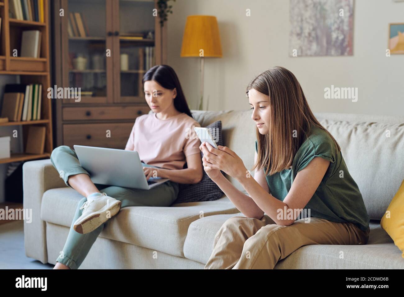 Cute teenage girl scrolling or texting in smartphone while sitting on ...