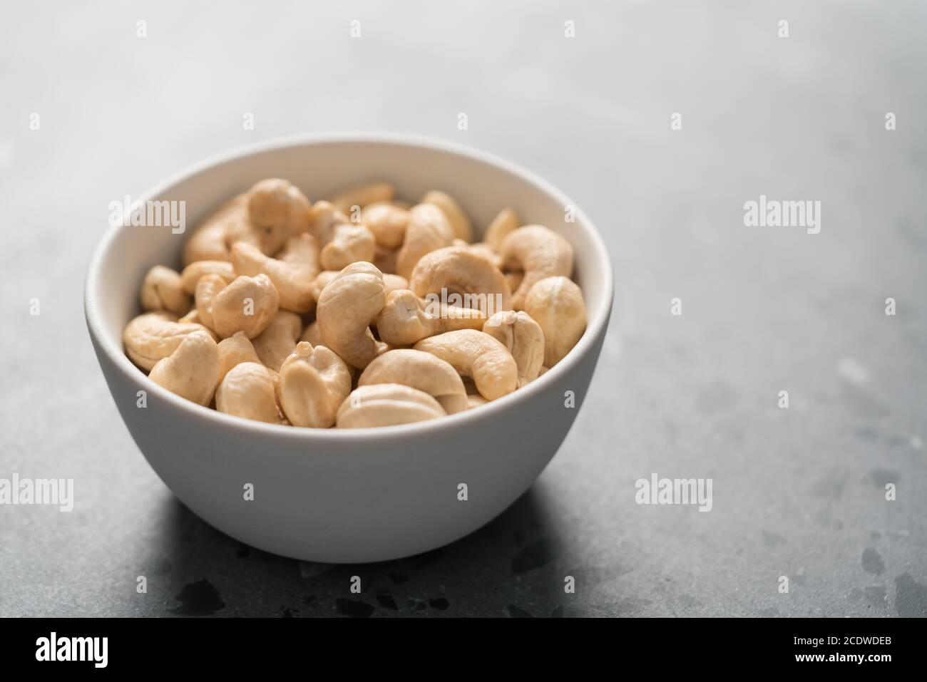 Dry cashew nuts in white bowl on concrete background with copy space ...