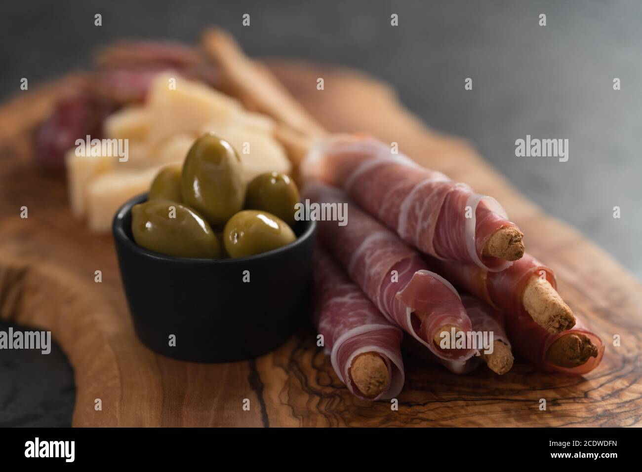 Italian snacks on olive wood board, shallow focus Stock Photo - Alamy