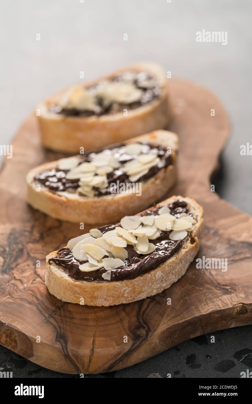 Rustic ciabatta with organic chocolate cream and almond flakes on olive ...