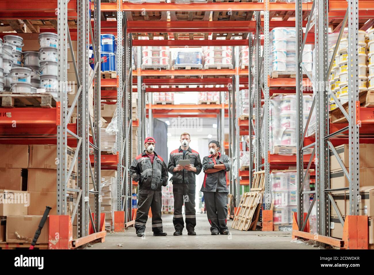 Group of intercultural warehouse workers in gloves, respirators and ...