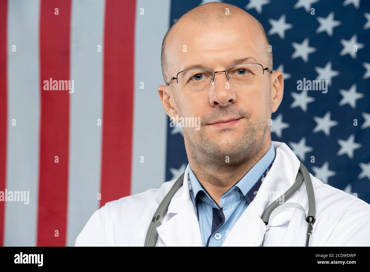 Middle aged contemporary doctor in eyeglasses looking at you against us ...