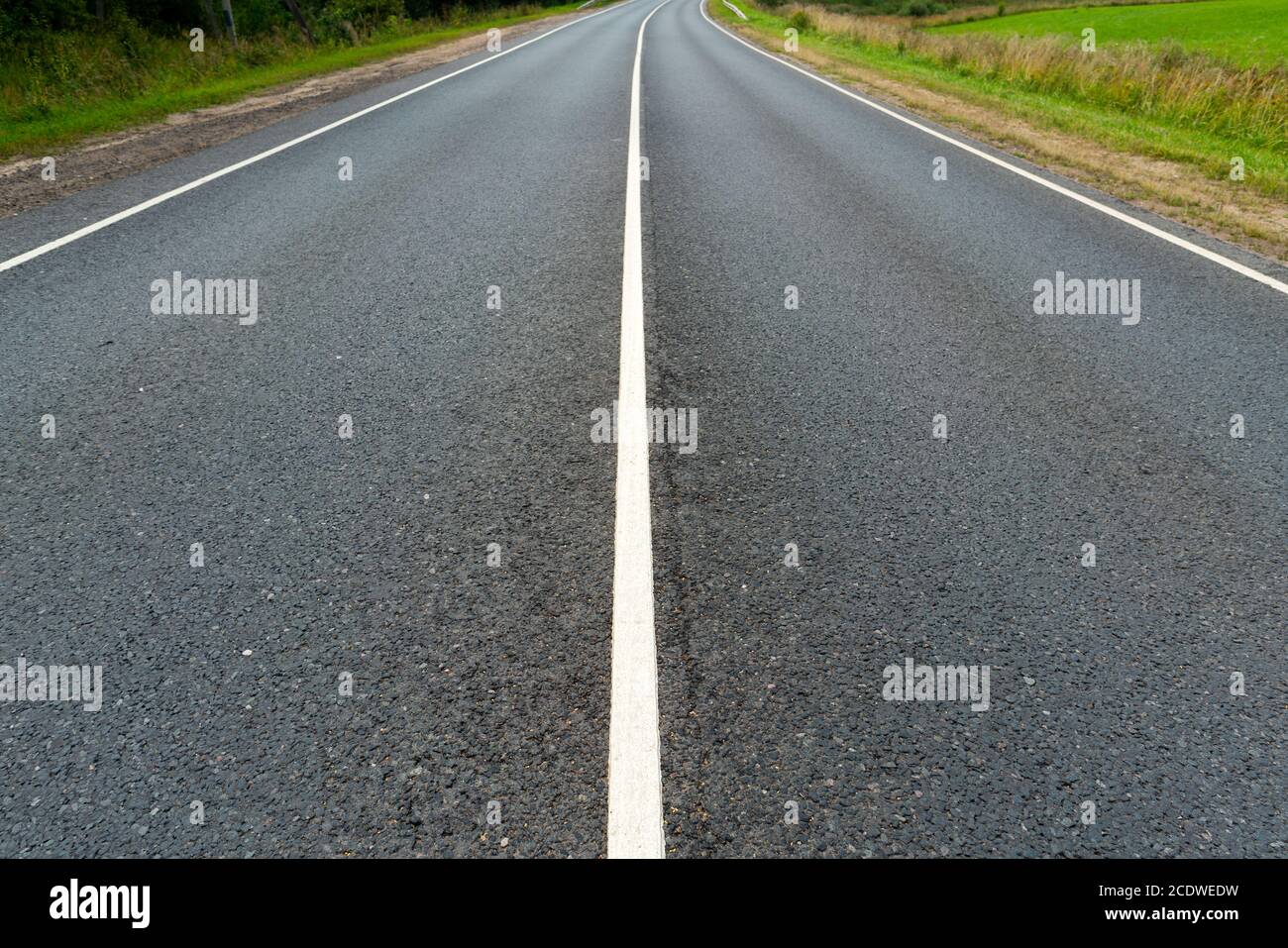 The dividing strip of an asphalt country road. White road markings ...
