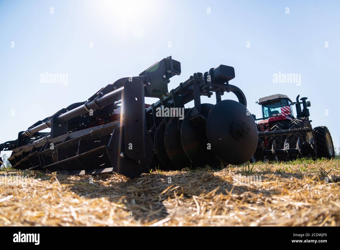 A tractor with a plow plows the field after harvesting Stock Photo - Alamy