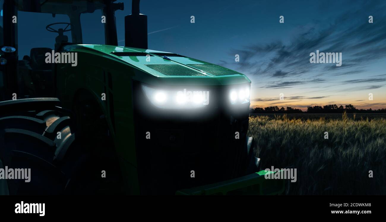Agricultural tractor with headlights at night Stock Photo - Alamy