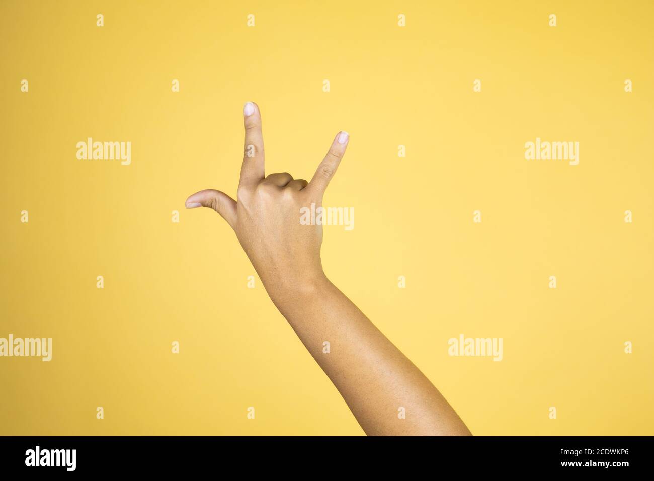 Hand over isolated yellow background doing rock symbol Stock Photo - Alamy