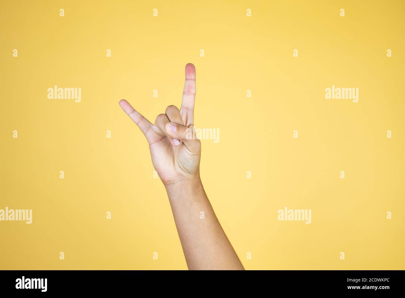 Hand over isolated yellow background doing rock symbol Stock Photo - Alamy