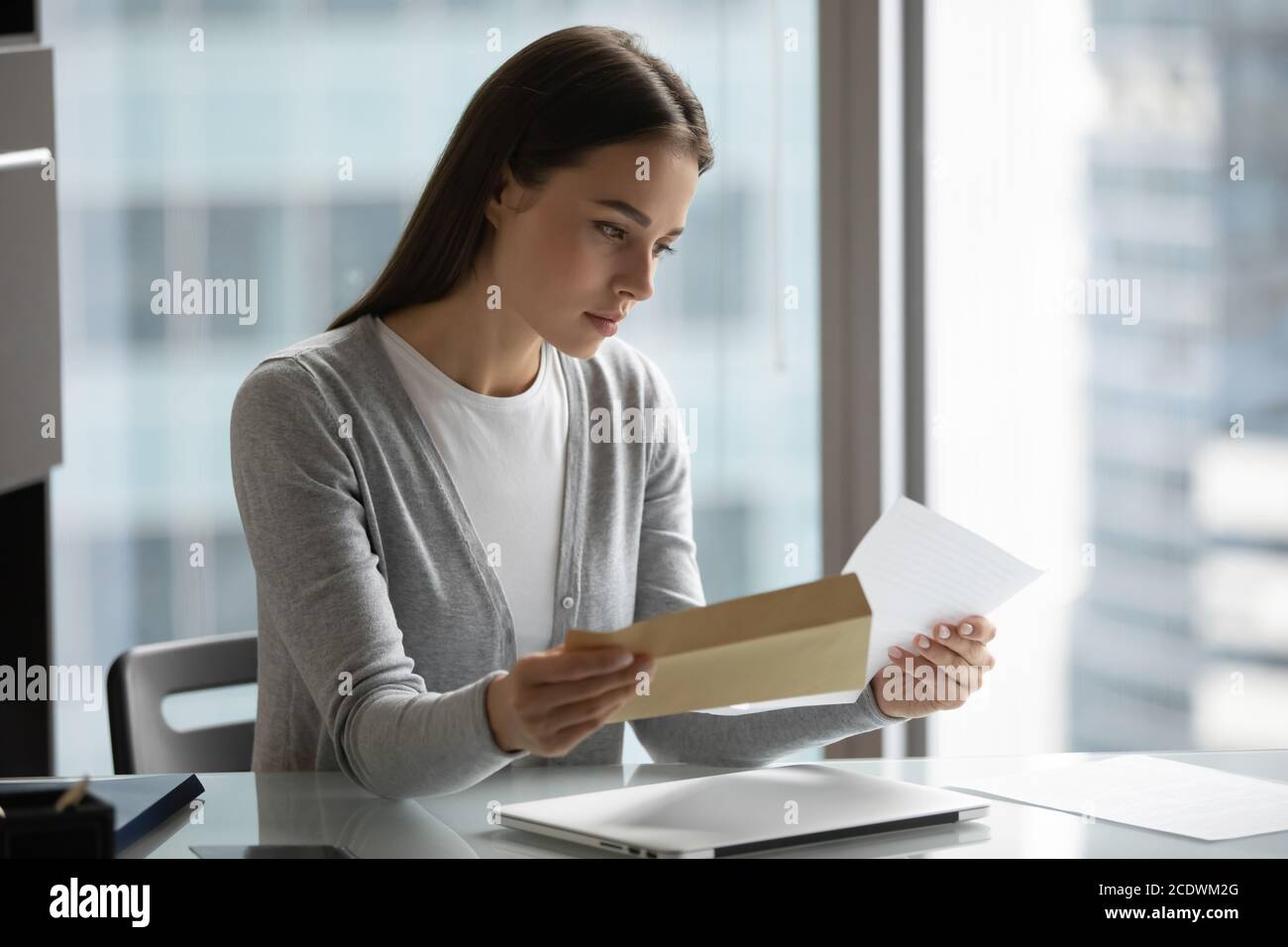 Serious confident businesswoman reading letter, holding open envelope ...