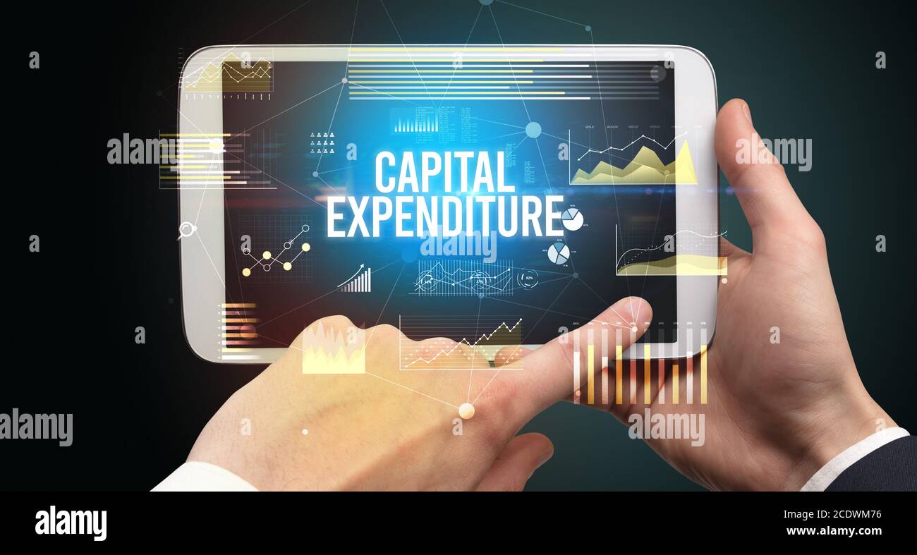 Close-up of hands holding tablet with CAPITAL EXPENDITURE inscription ...