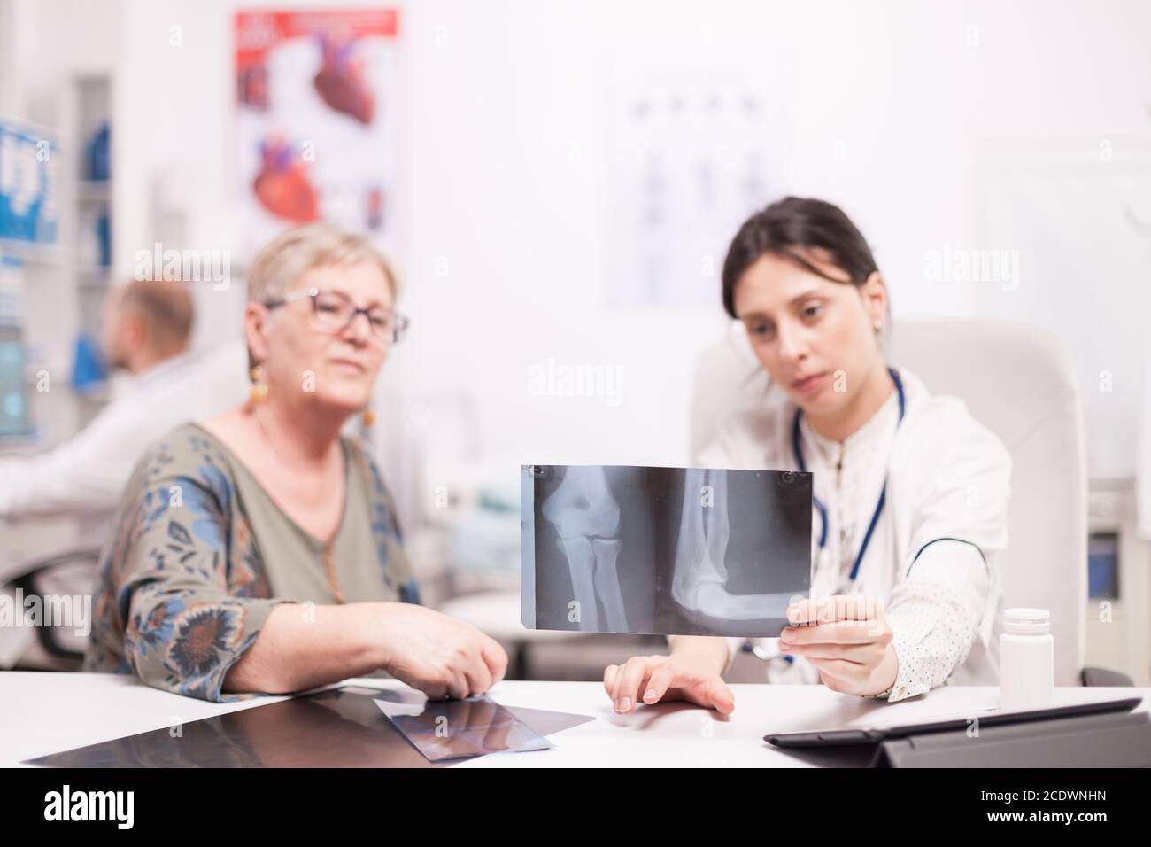 Doctor discussing with senior patient about her leg injury while ...