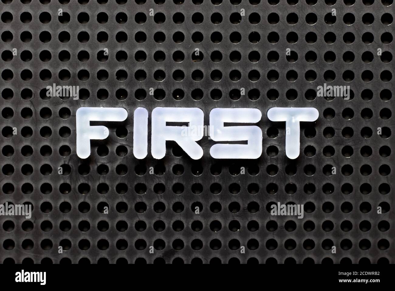 White color alphabet with word first on black pegboard background Stock ...