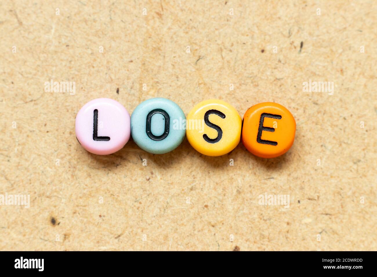 Round color bead with black letter in word lose on wood background ...