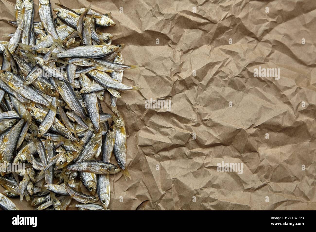 Dried small salted fish heap on crumpled paper, top view, copy space ...
