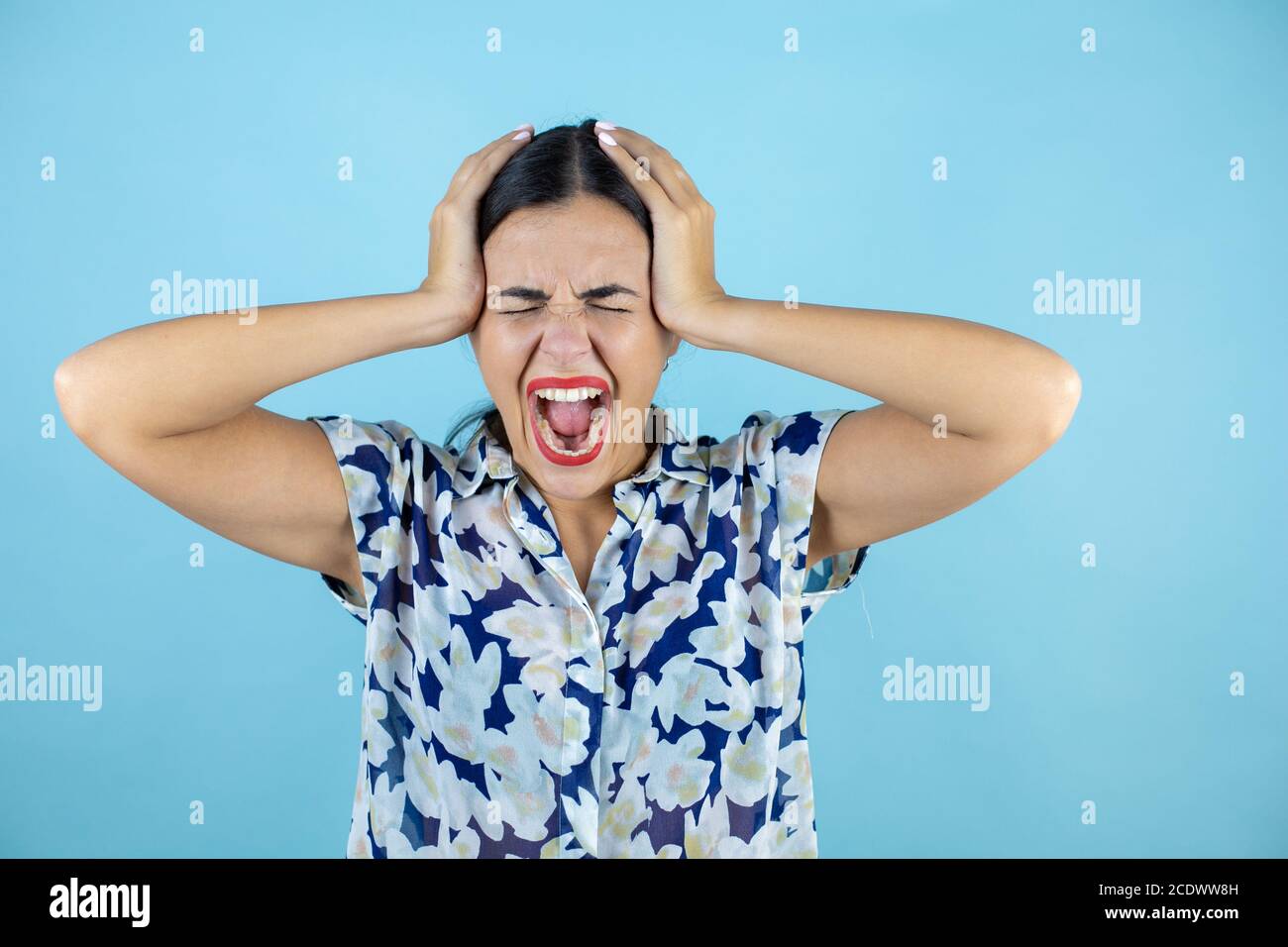 Young beautiful woman crazy and scared with hands on head, afraid and ...