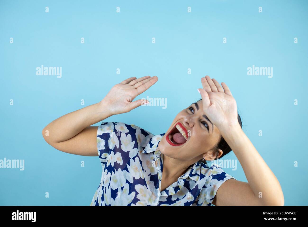 Young beautiful woman standing over blue isolated background scared ...