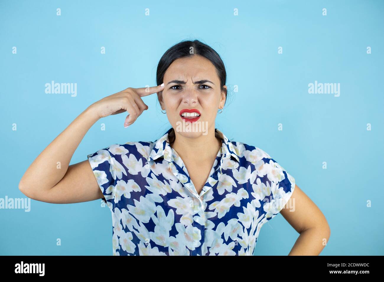Pretty woman with a confused face over blue background Stock Photo - Alamy