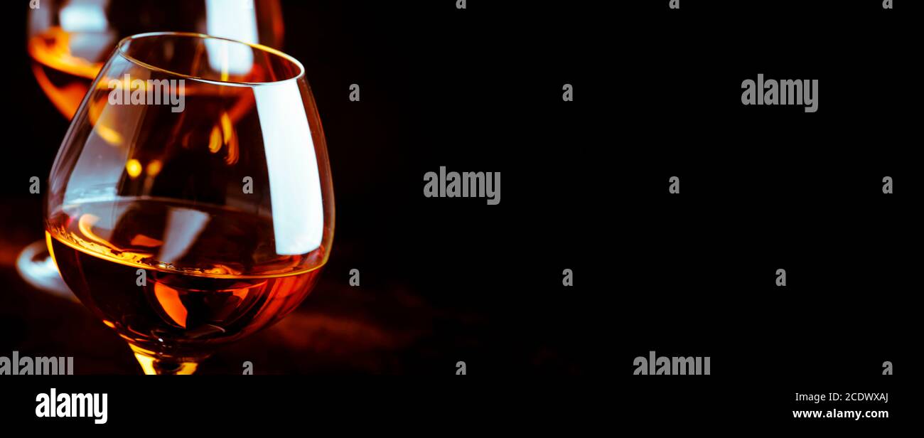 Grape brandy in shot glass, dark brown background. Panoramic banner ...