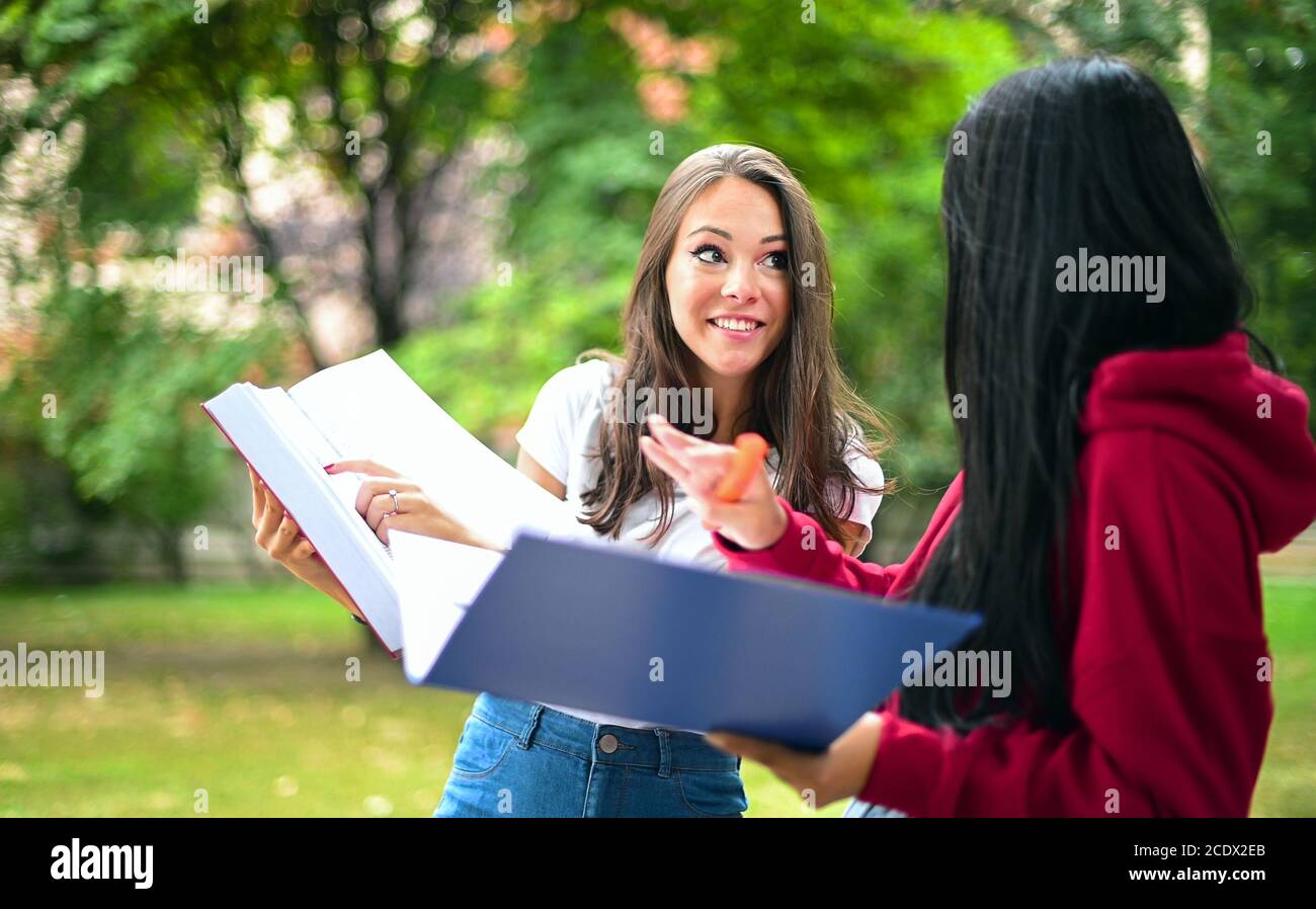Two female schoolmates talking in a college courtyard Stock Photo - Alamy