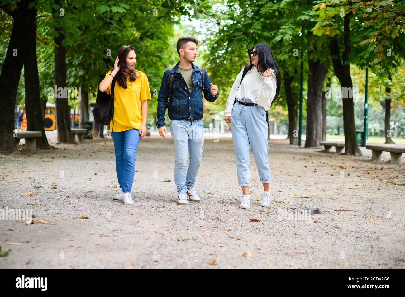 Happy students outdoor walking and talking to each other, full length ...