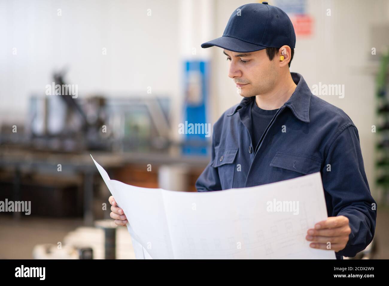Blue dressed engineer reading a bluepring drawing in an industrial ...