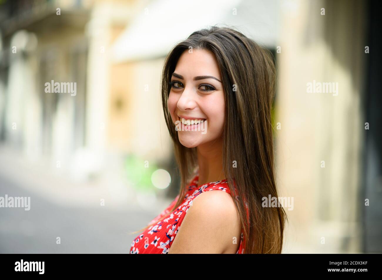 Beautiful charming young lady waking in a cuty street and looking back ...