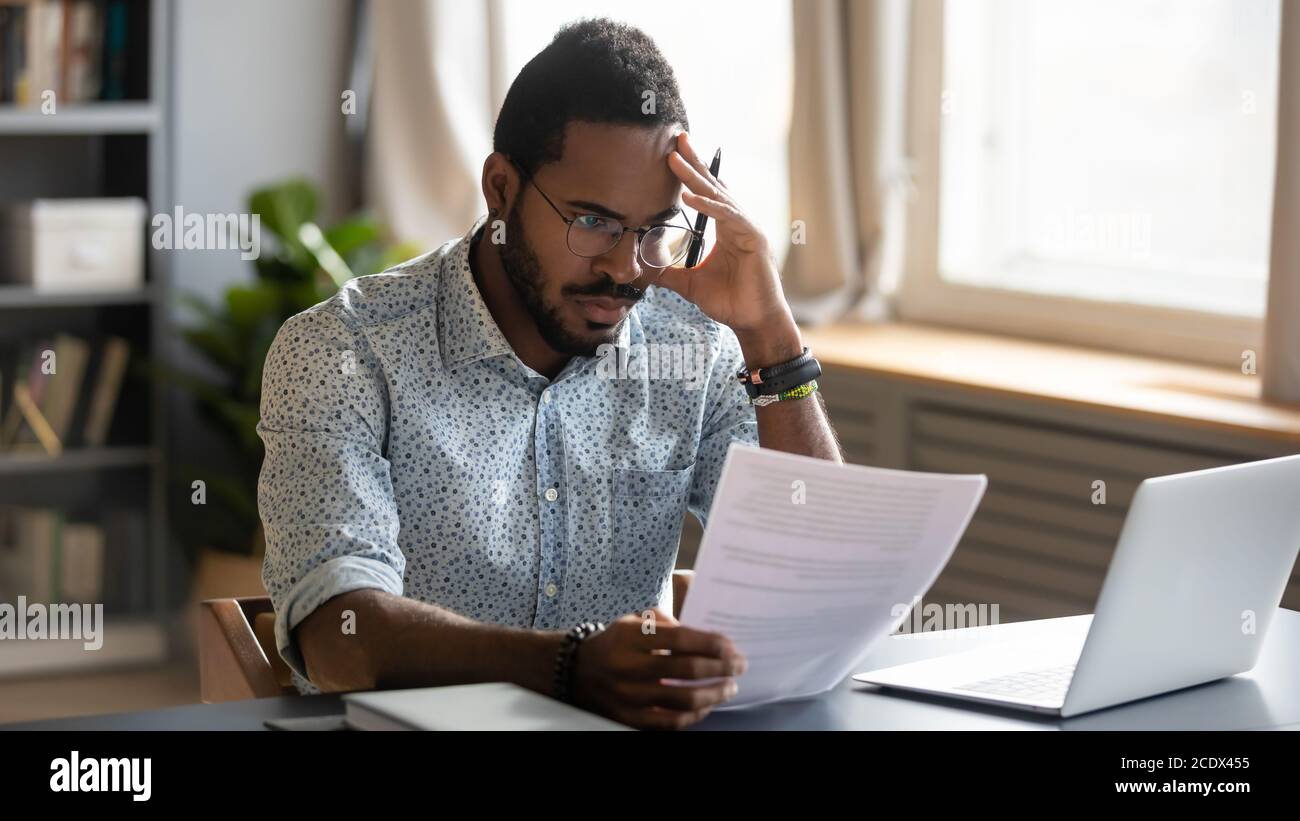 Stressed dissatisfied African American man reading letter with bad news ...