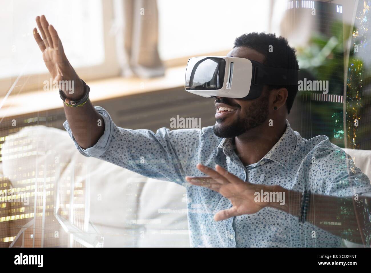 Smiling African American man in VR glasses enjoying augmented reality ...