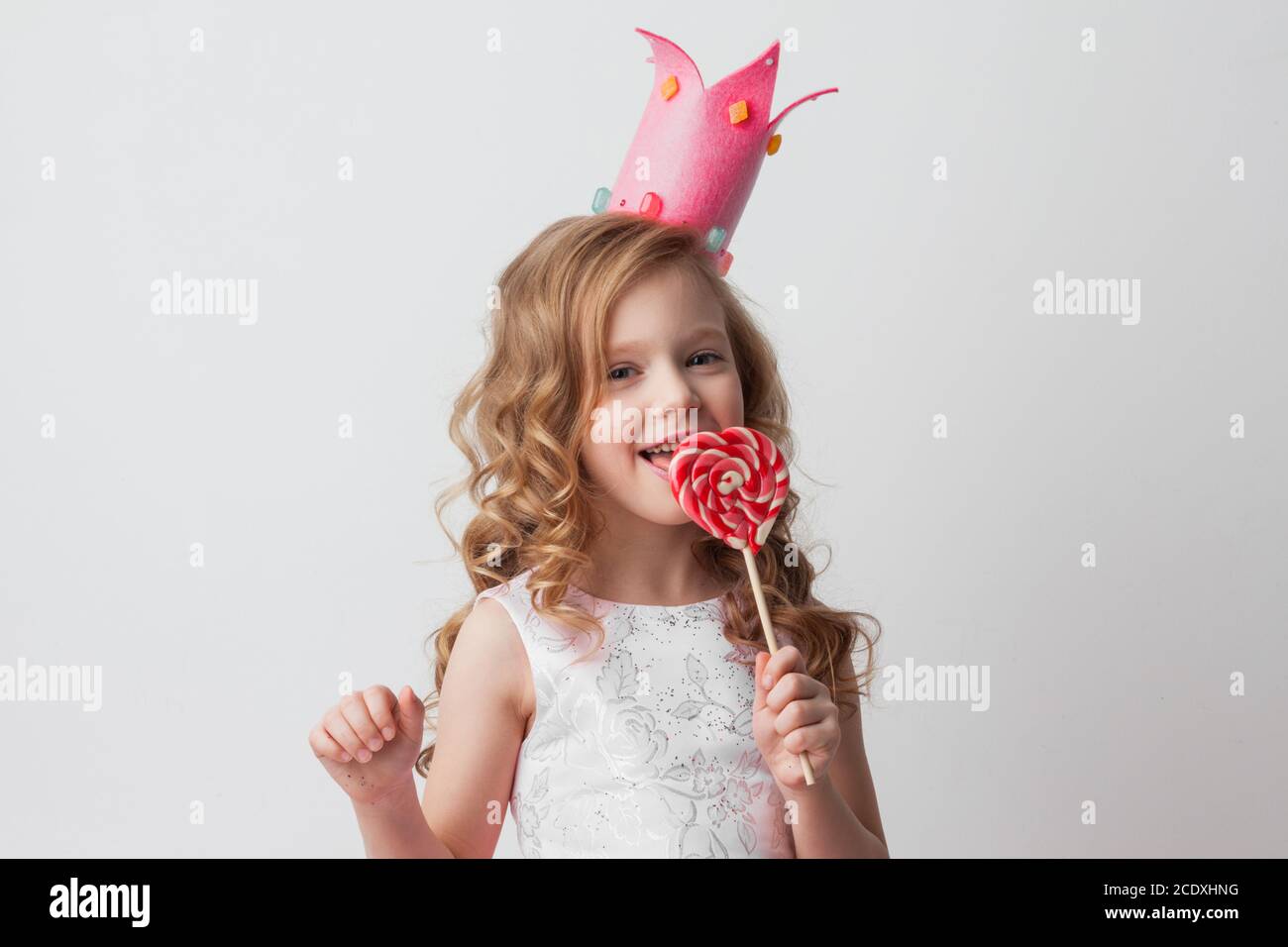 Beautiful little candy princess girl in crown lick big pink heart ...