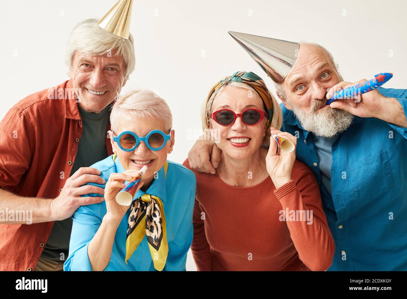 Portrait of senior people in party hats and sunglasses smiling at ...