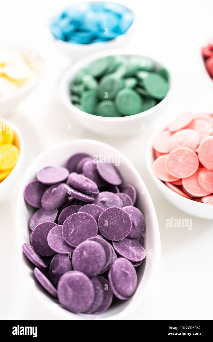 Rainbow colors of round chocolate chips in a white bowls for melting ...