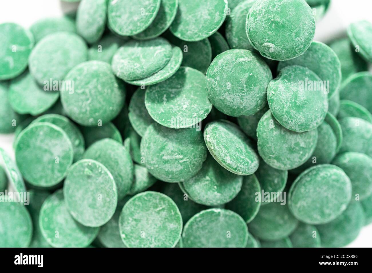 Green round chocolate chips for melting chocolate shapes on a white ...