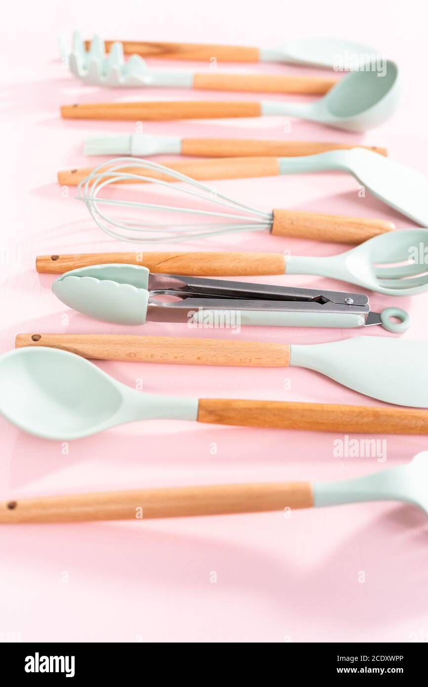 New blue silicone kitchen utensils with wooden handles on a pink ...