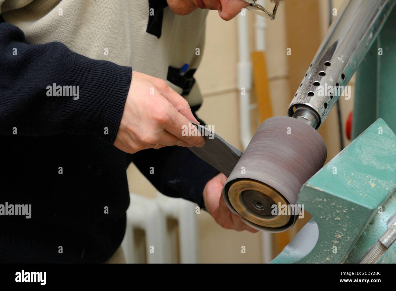 Worker sands wooden blank using a belt grinding machine for further ...