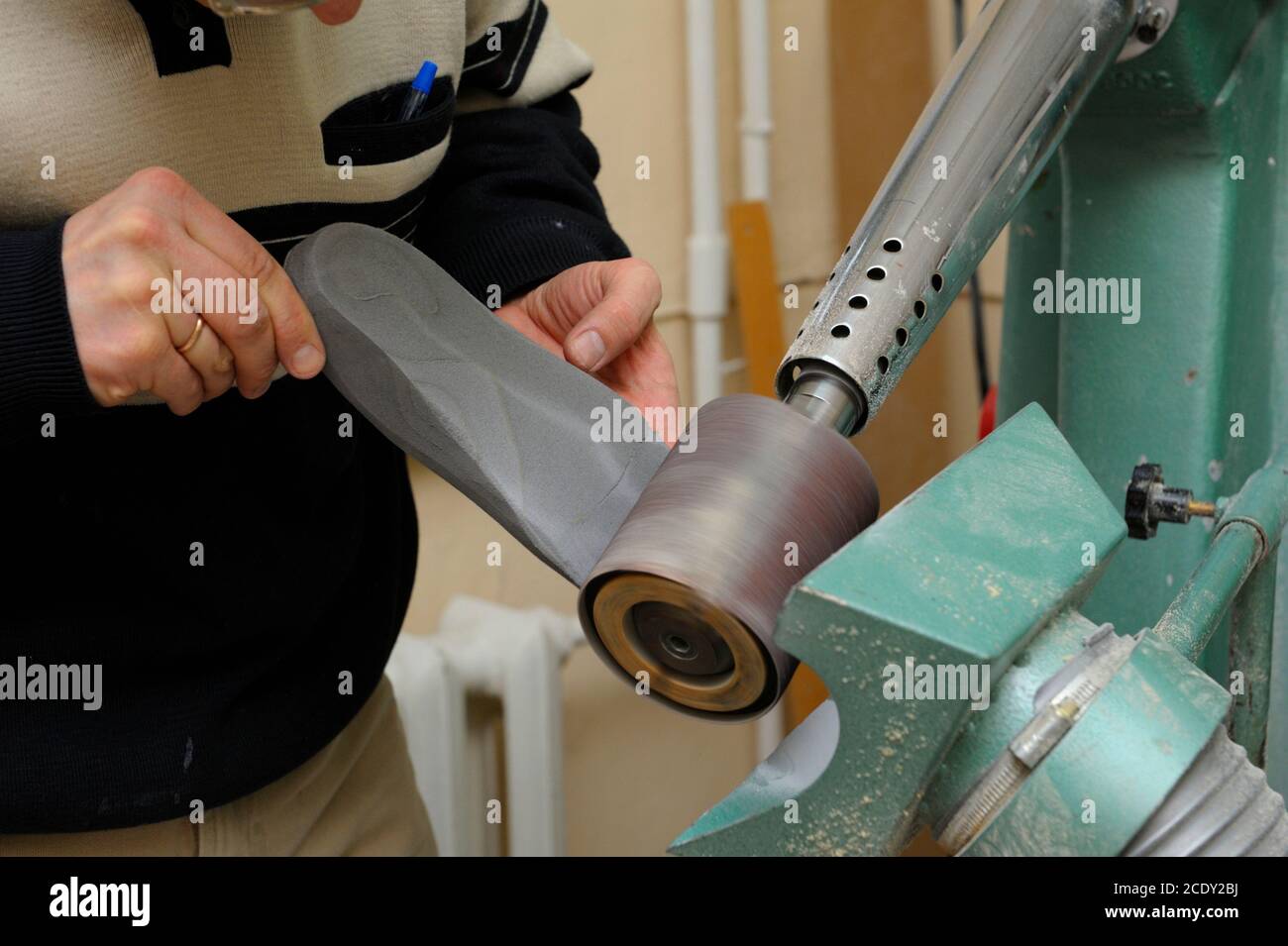 Worker sands wooden blank using a belt grinding machine for further ...