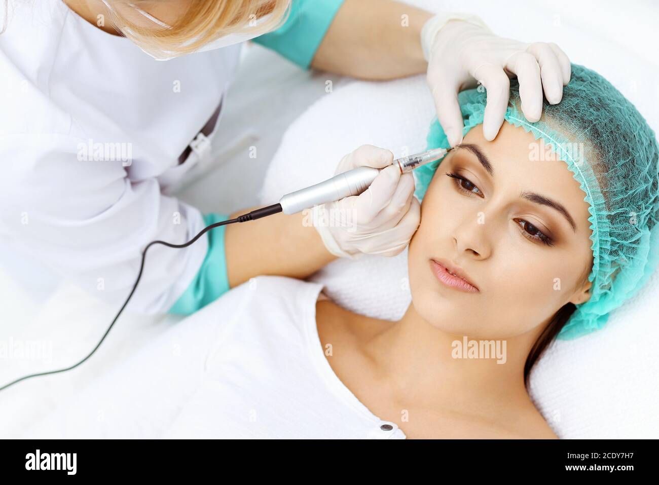 Professional beautician doing eyebrow tattoo at woman face. Permanent ...