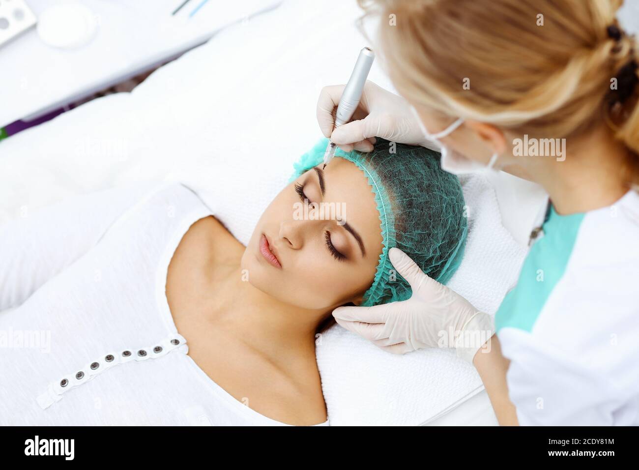 Professional beautician doing eyebrow tattoo at woman face. Permanent ...