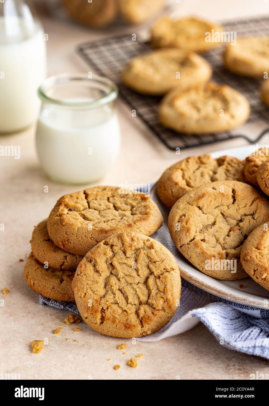 Peanut butter cookies in a stack and plate with glass of milk in ...