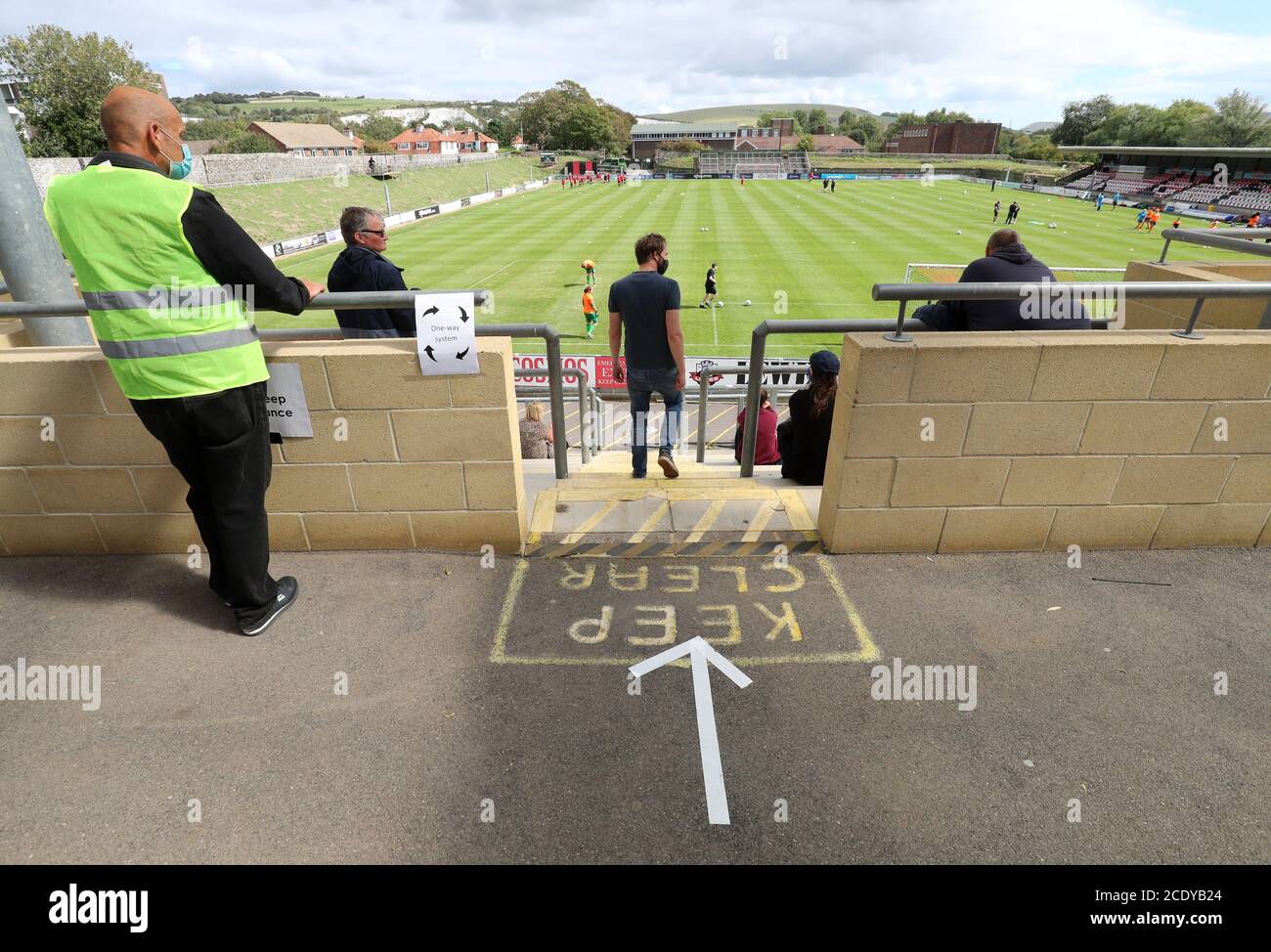 A steward in PPE in front a a marked fan area during the pre-season ...