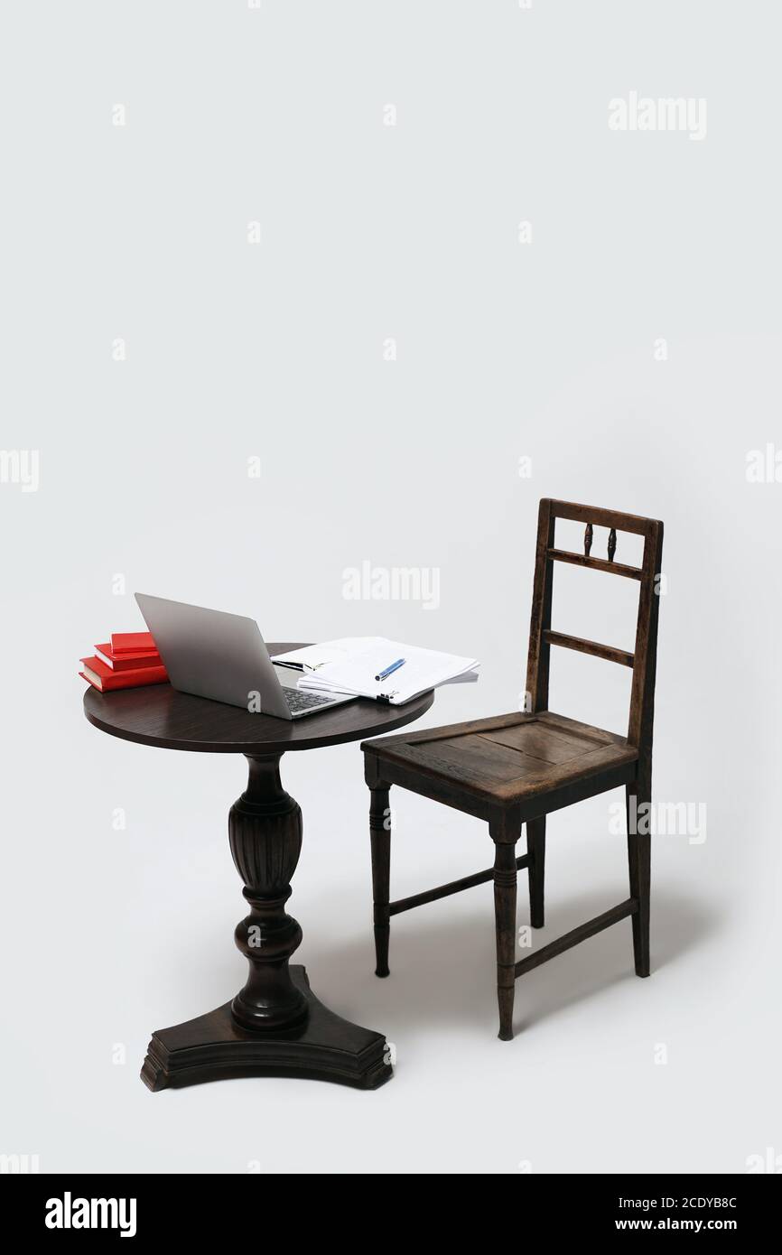 Empty table and chair with laptop computer books and paper notes ...