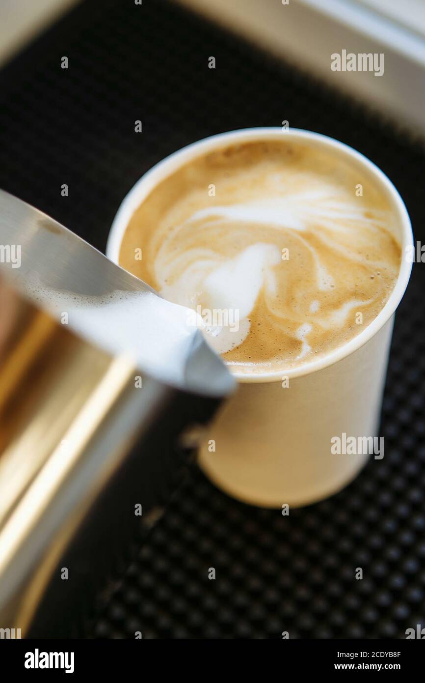 Barista draws milk over a coffee - making latte art for cappuccino ...