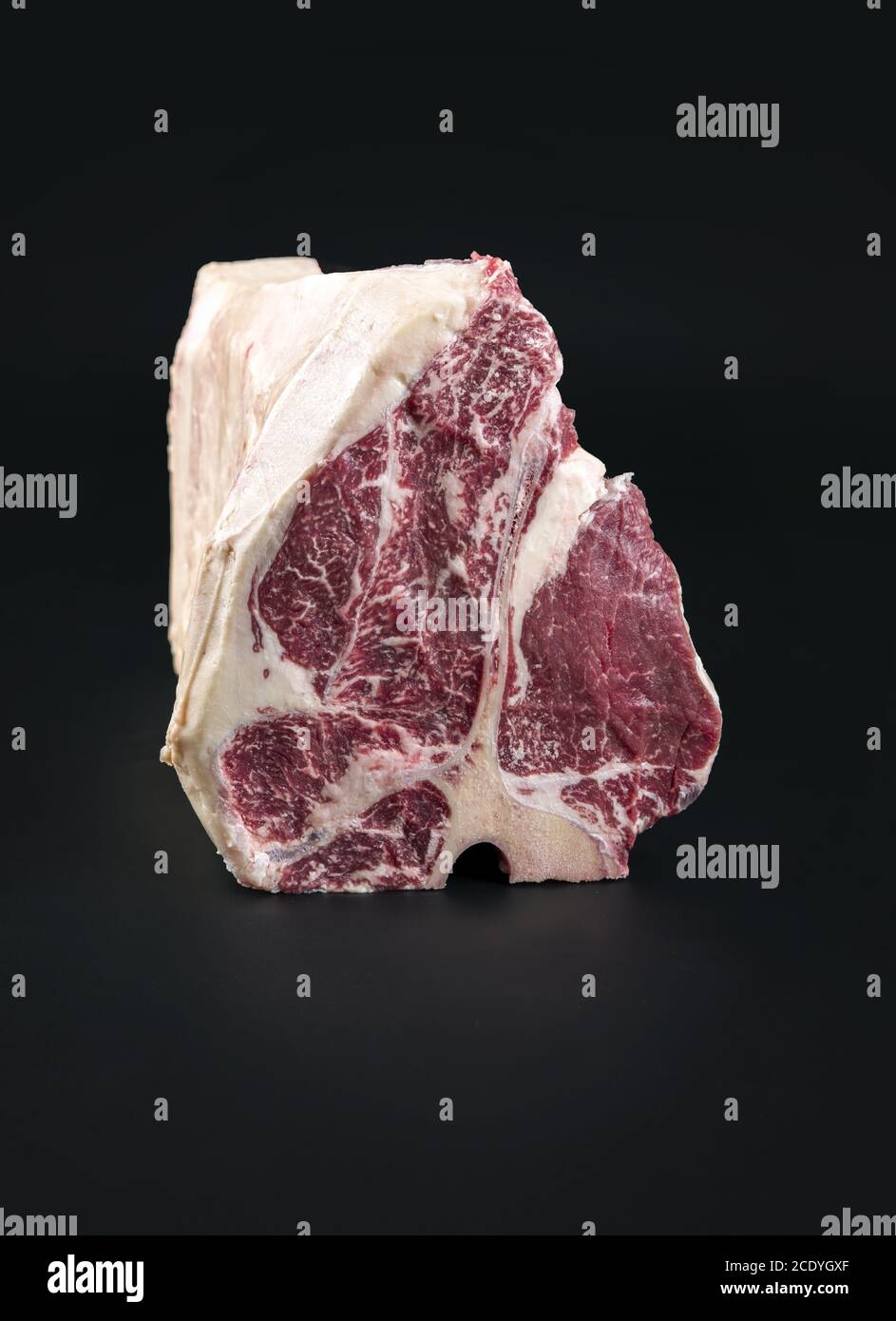 Raw dry aged wagyu porterhouse beef block offered as closeup on black ...