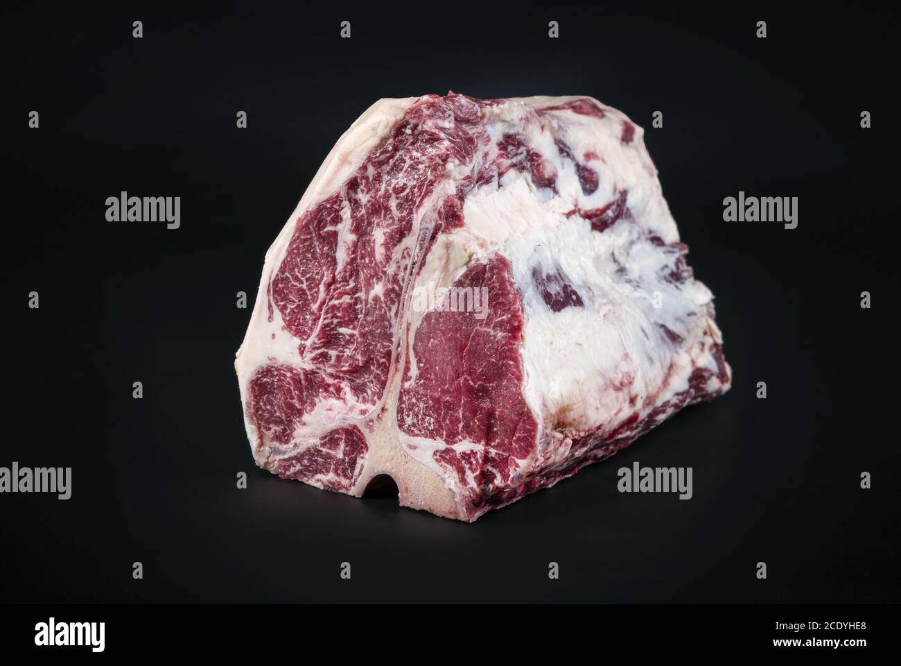 Raw dry aged wagyu porterhouse beef block offered as closeup on black ...