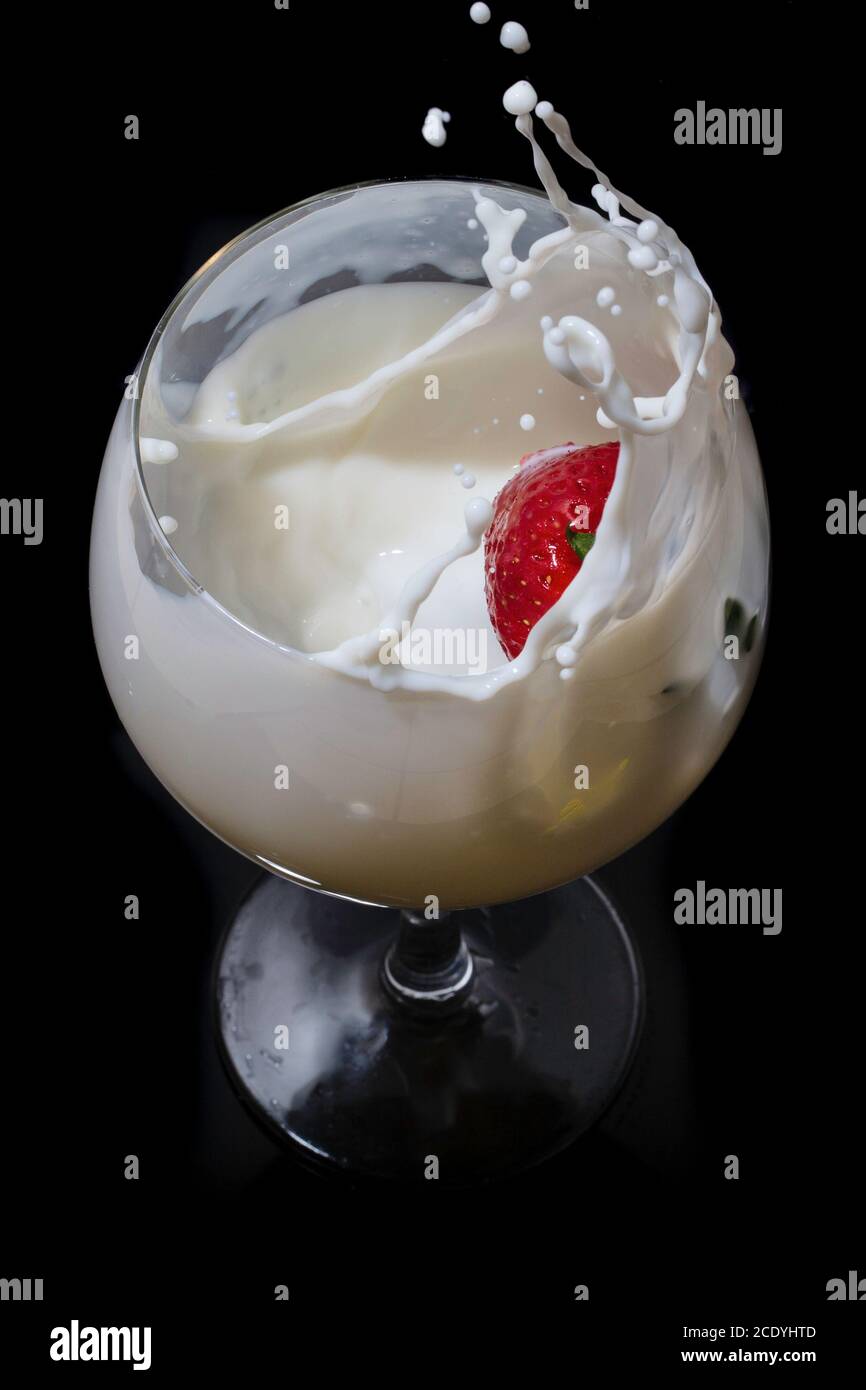 Strawberry Splashing on a Wide Gin Glass Full of Milk Stock Photo - Alamy