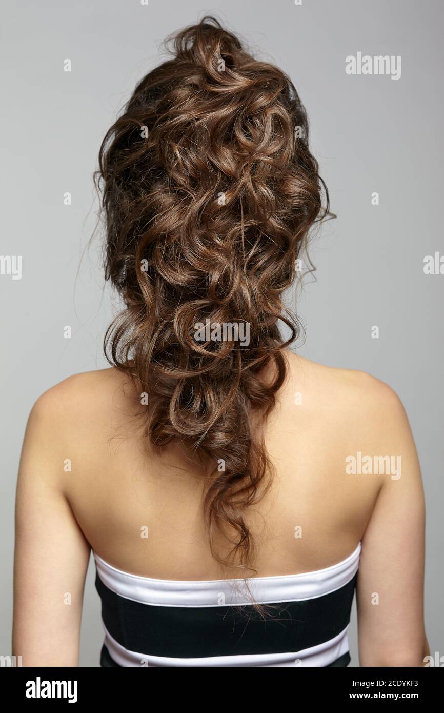 Back view portrait of beautiful young dark brunette woman on gray ...
