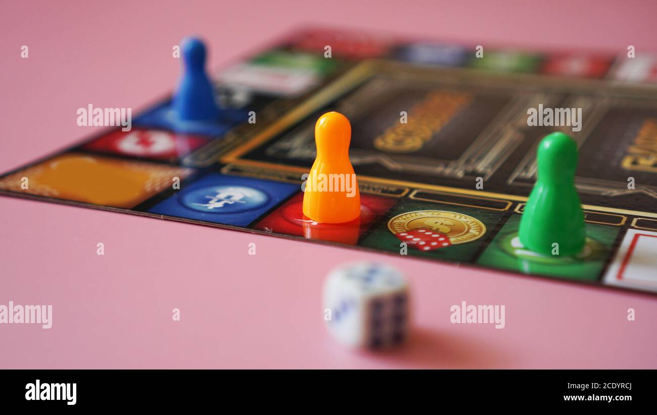 Colored board game figures with dice on pink background Stock Photo - Alamy