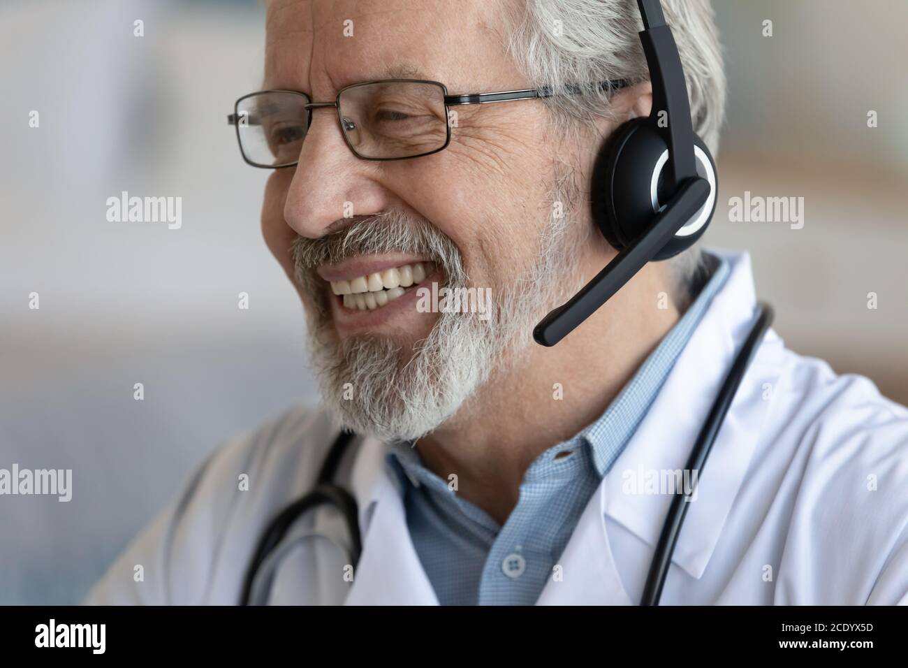 Close up smiling mature doctor wearing headset working online Stock ...