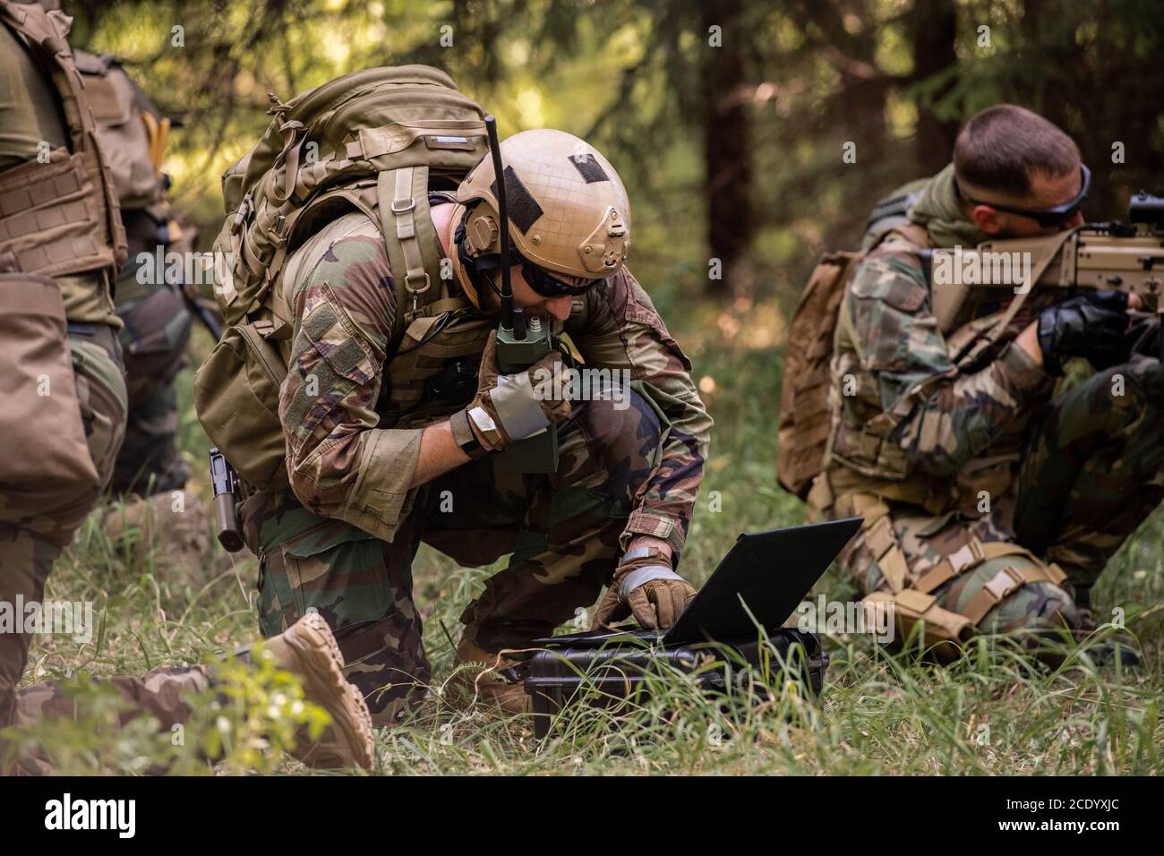 Busy soldier with backpack using military laptop while passing ...