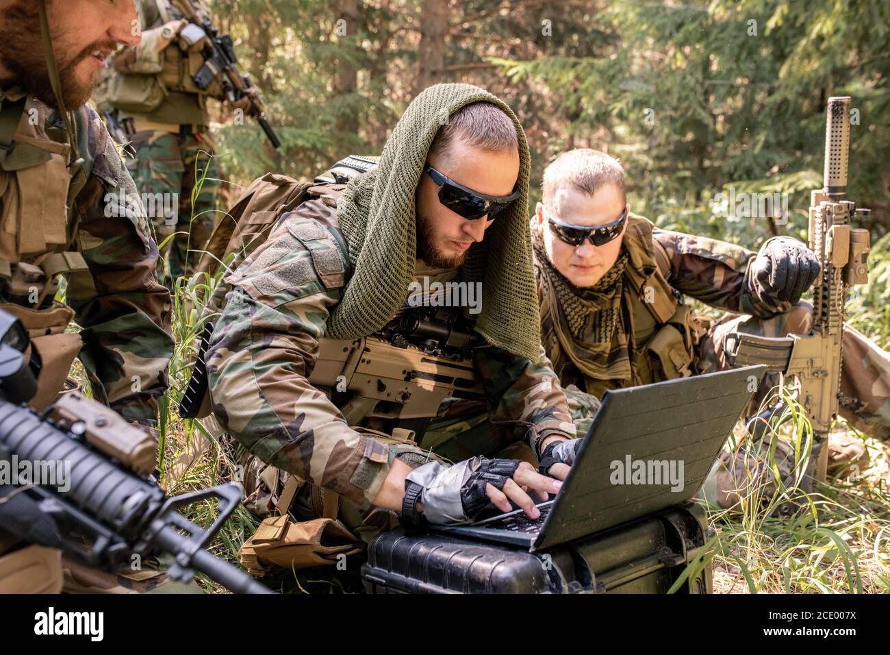Concentrated army programmer in sunglasses using military computer ...