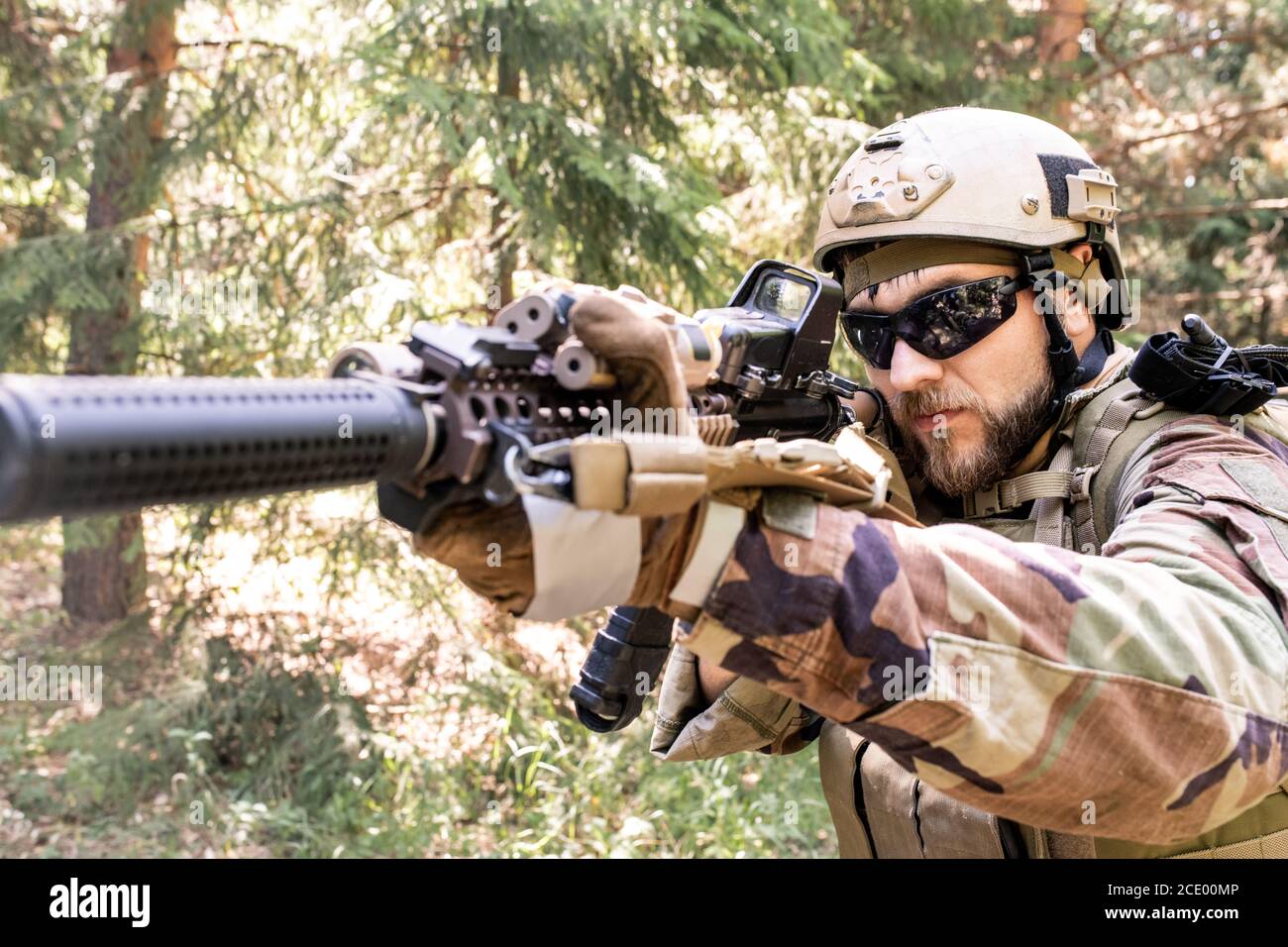 Bearded sniper in sunglasses and helmet focused on target looking ...